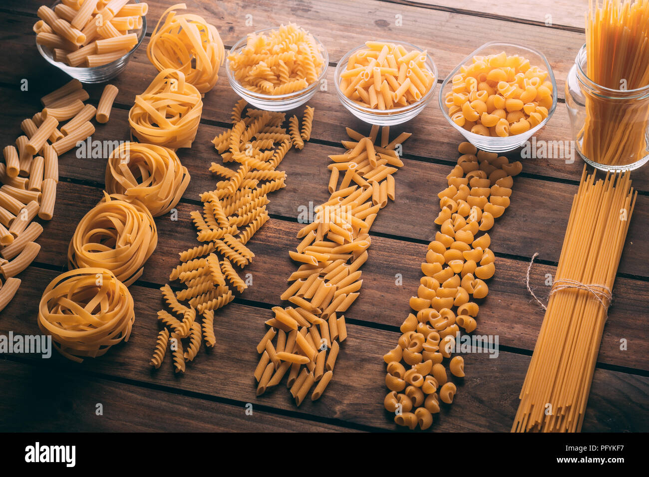 Top view of a rustic wooden table full of different types of pasta ...