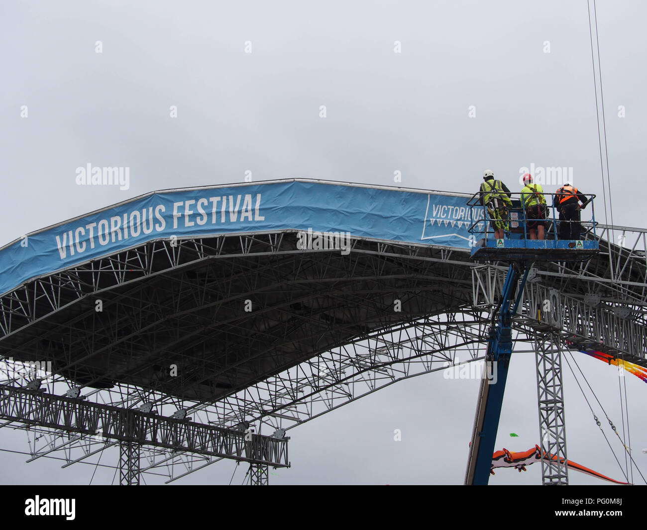 Three workers in a cherry picker assisting in the huilding of a stage ...