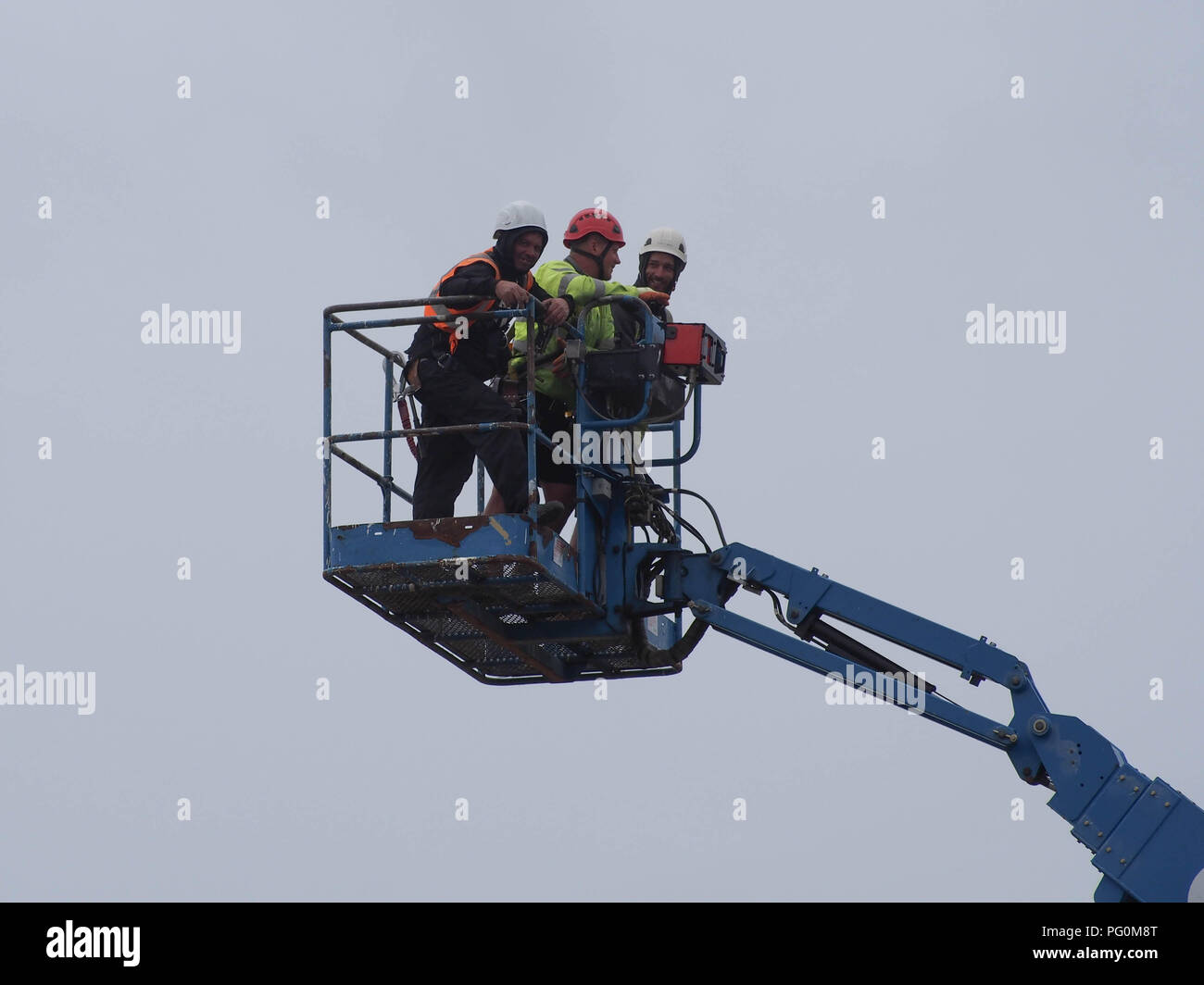 Three workers in a cherry picker assisting in the huilding of a stage ...