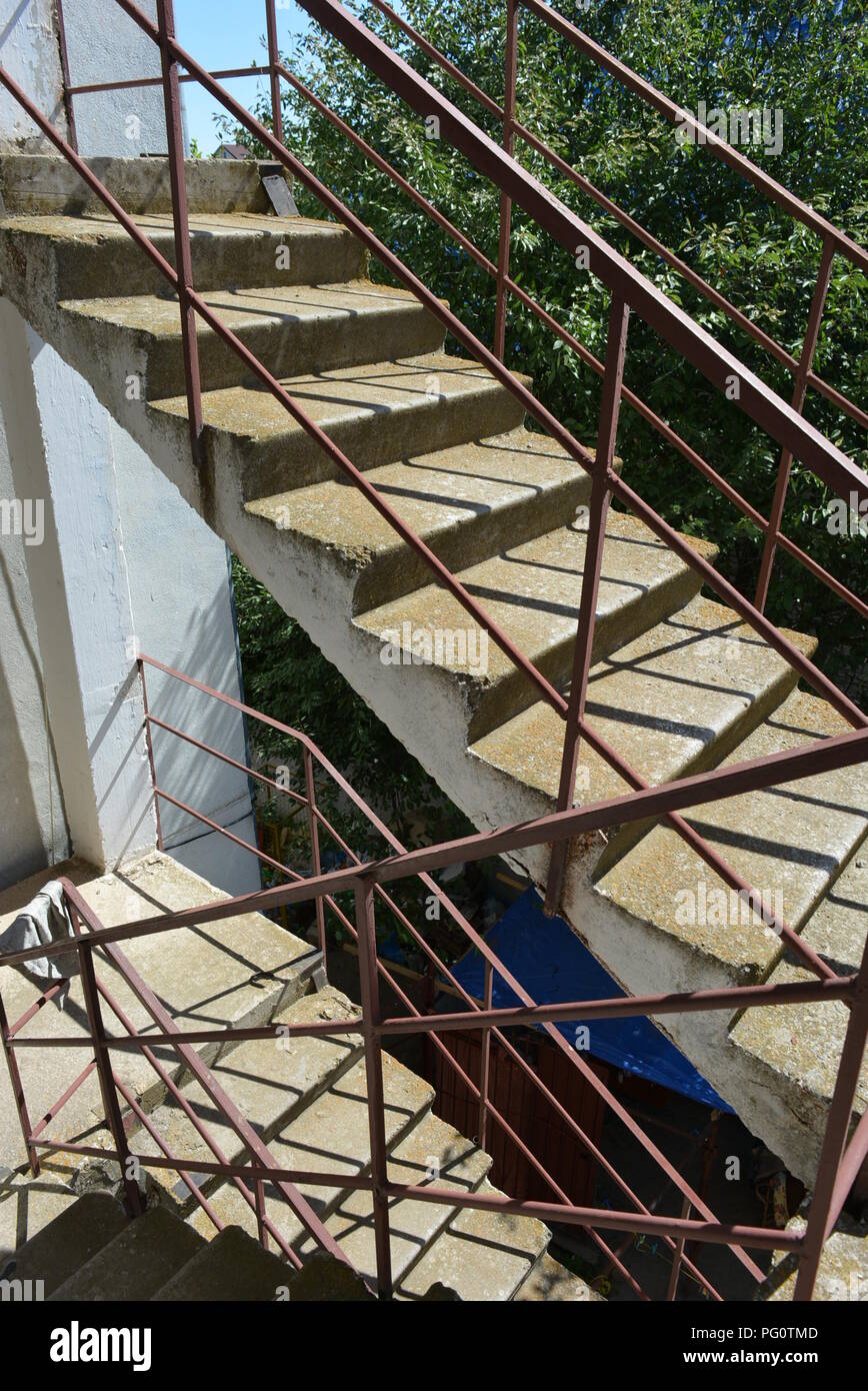 Emergency fire concrete staircase with metal handrails in the sunlight ...