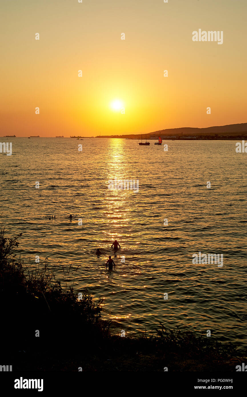 Golden sunset on the sea, the path on the water. People are swimming ...