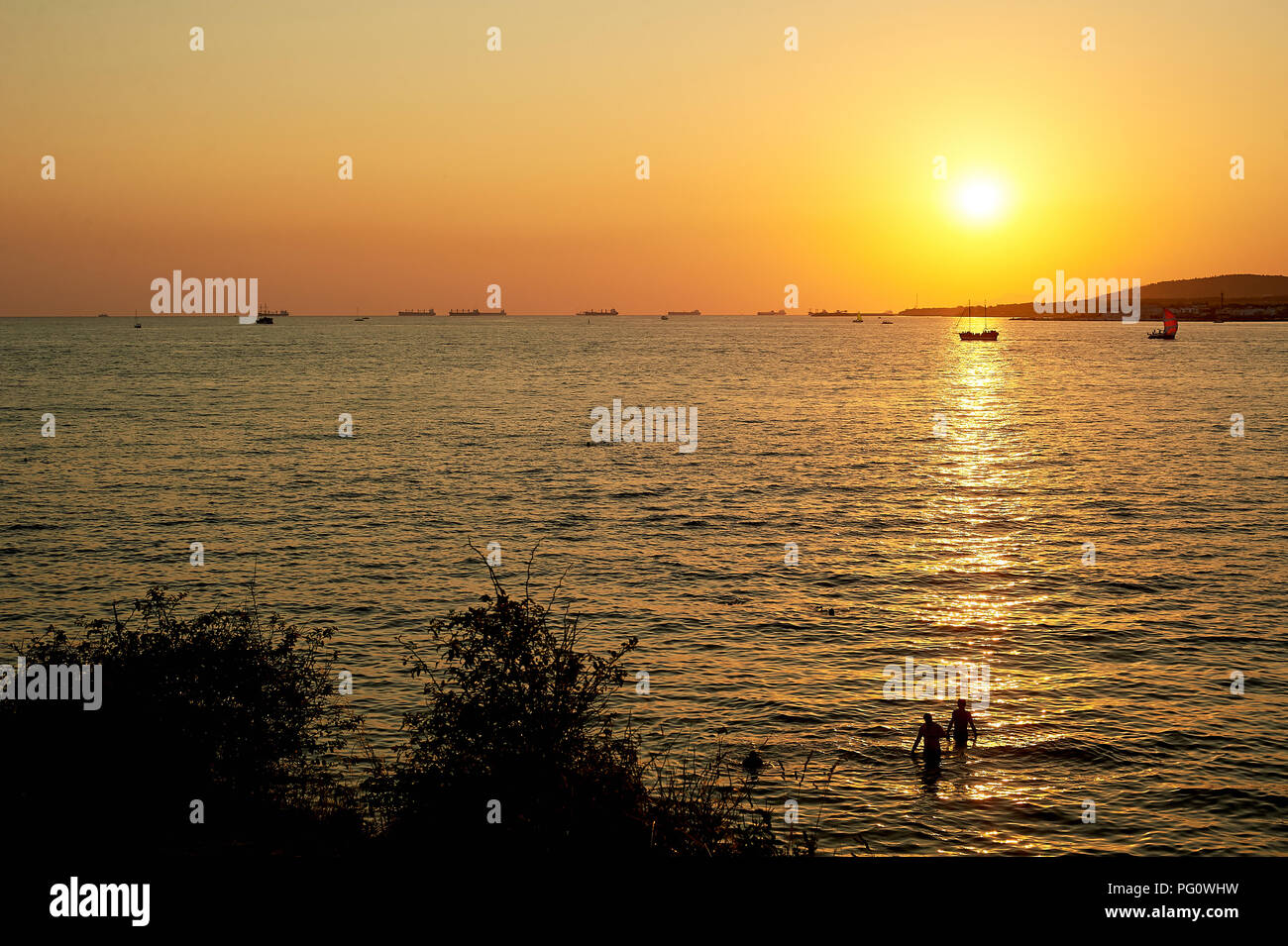 Golden sunset on the sea, the path on the water. People are swimming ...