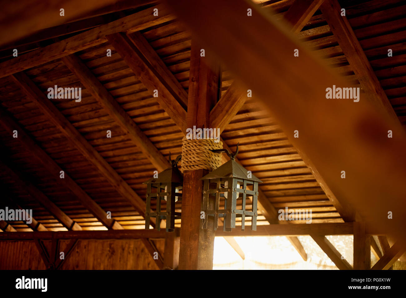 Massive metal lantern under a wooden canopy. The beam is wound with a ...