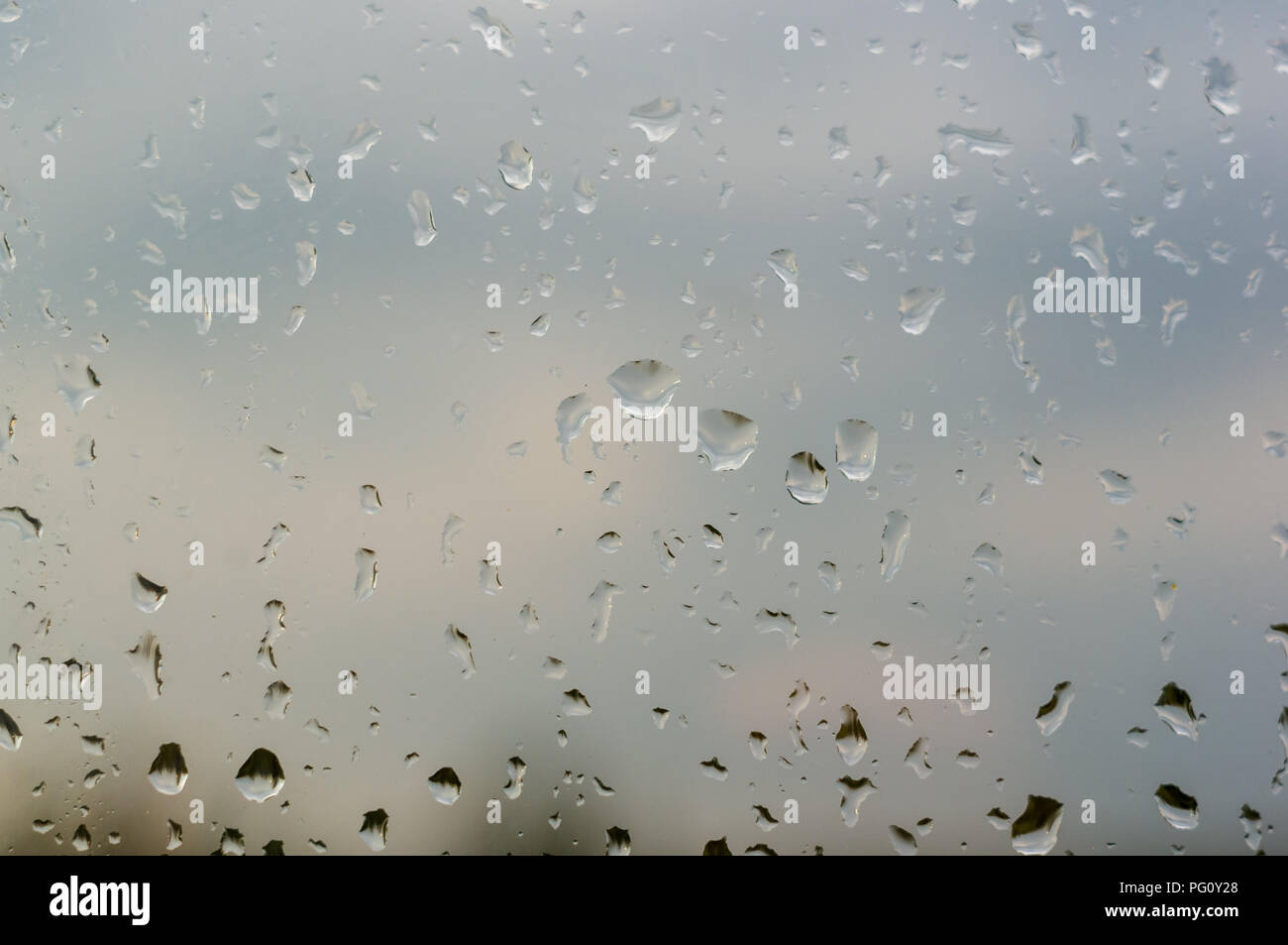 raindrops on window glass on background of cloudy sky and landscape ...
