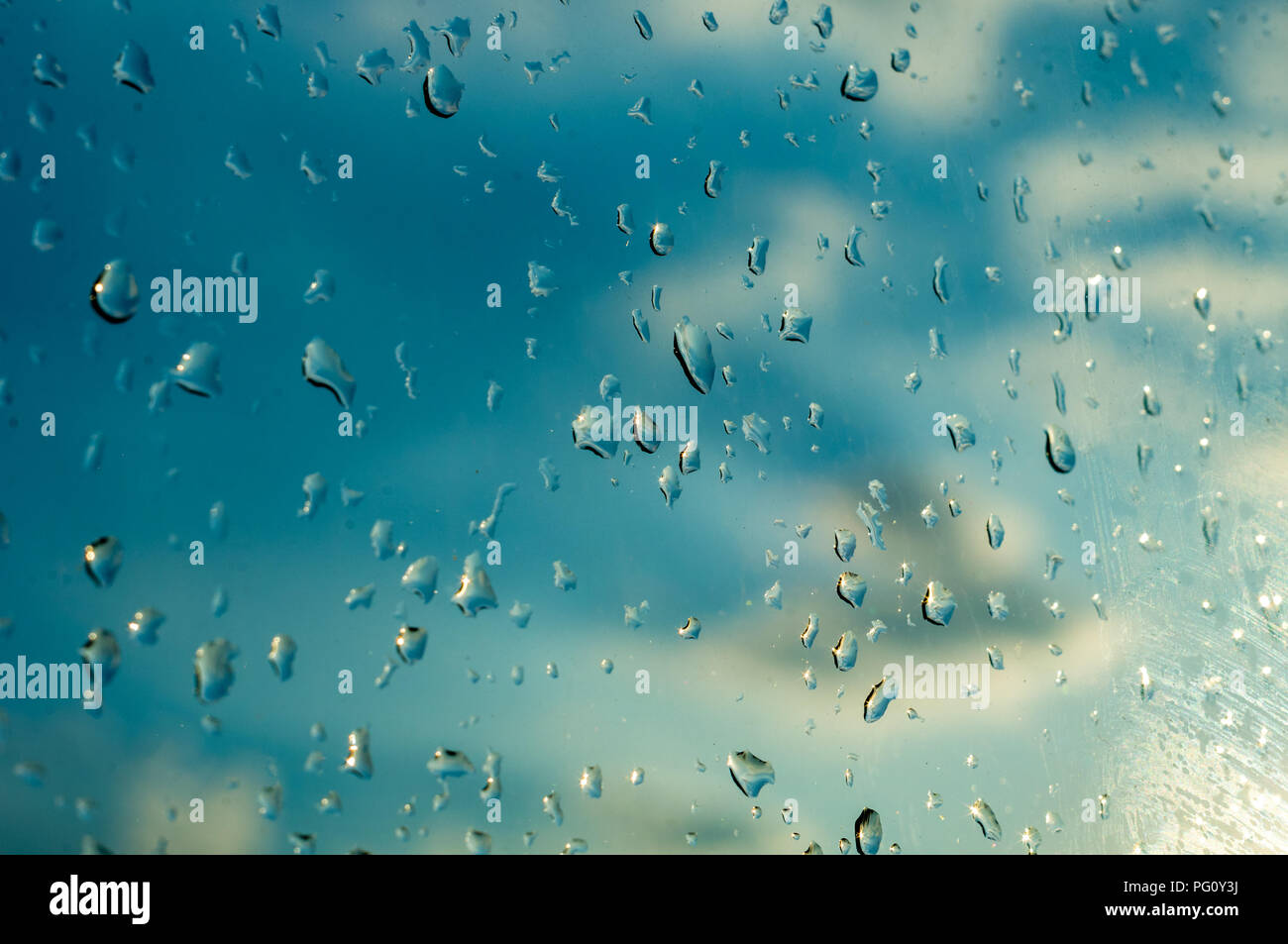 raindrops on window glass on background of cloudy sky and landscape ...