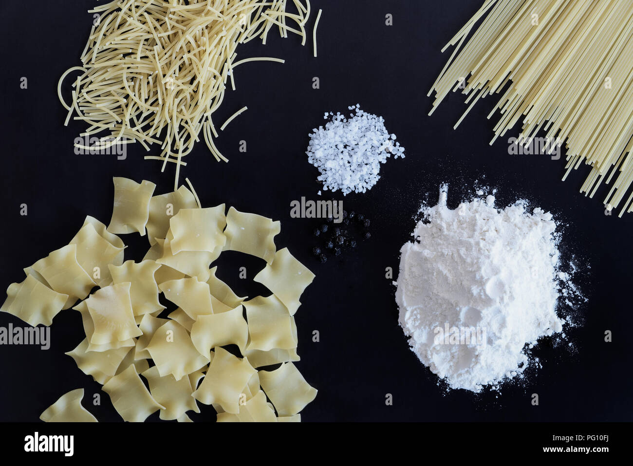 Three different types of pasta, pile of flour, salt and pepper are laid ...