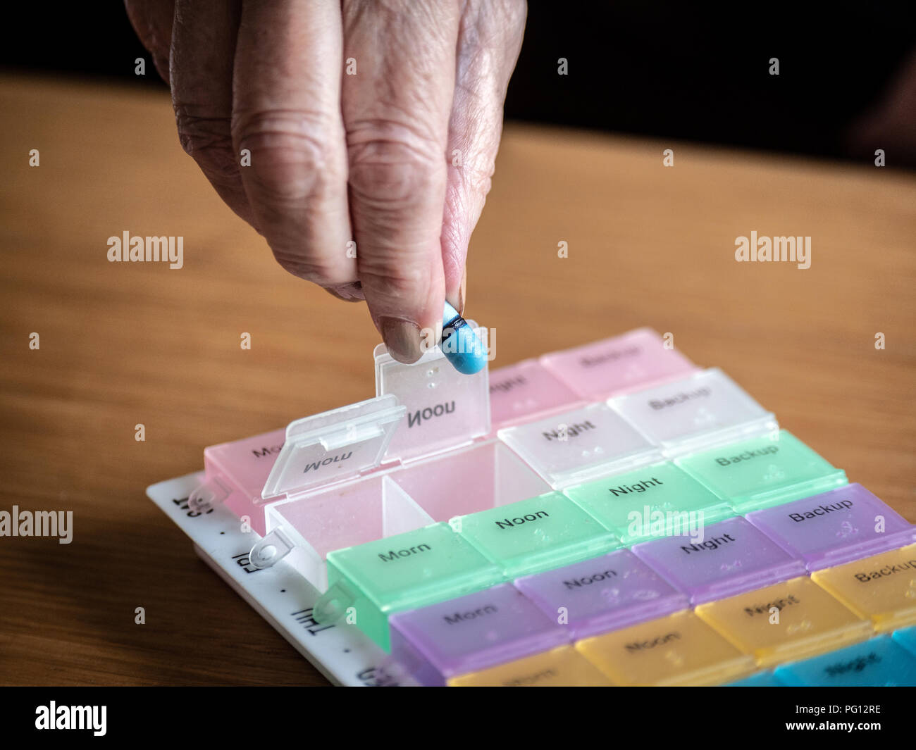 Mature lady placing tablets into weekly tablet dispenser Stock Photo ...