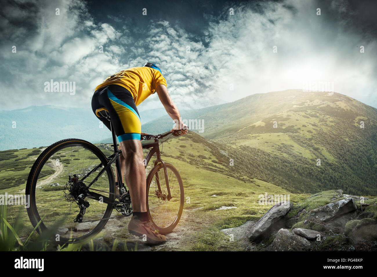 The young fit man in helmet conquering mountains on a bicycle. The bike ...