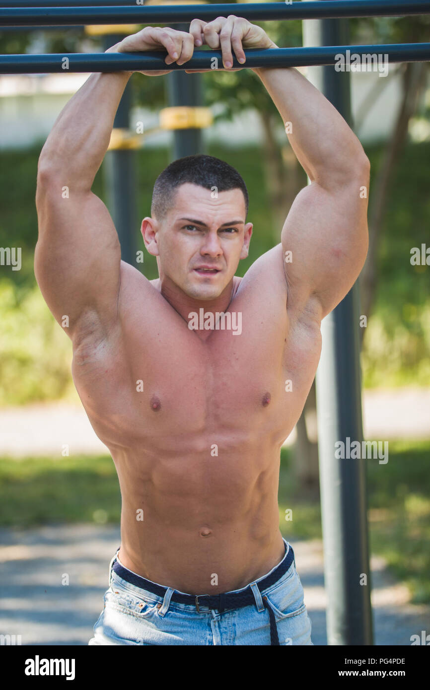 A man with a beautiful inflated body during training on the bar in the ...
