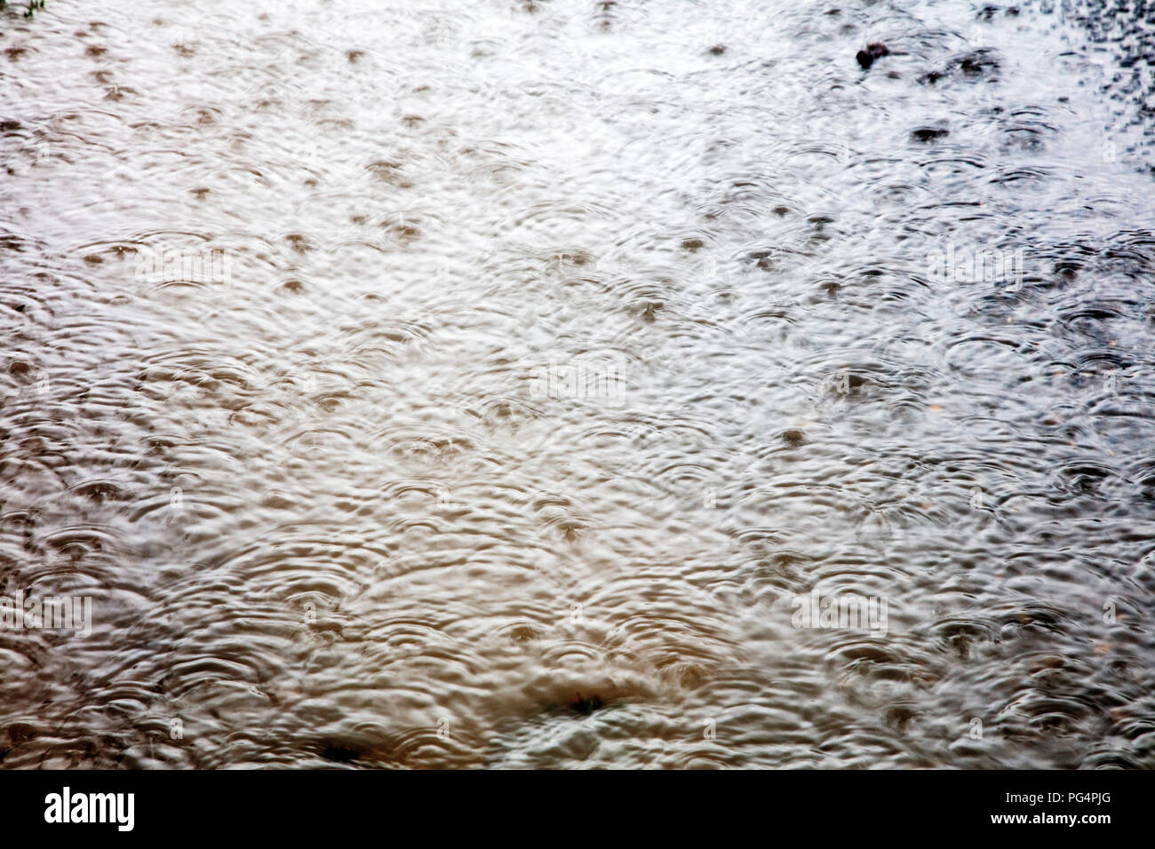 Heavy Rain Falling Into a Puddle on a Road in West Sussex Stock Photo ...