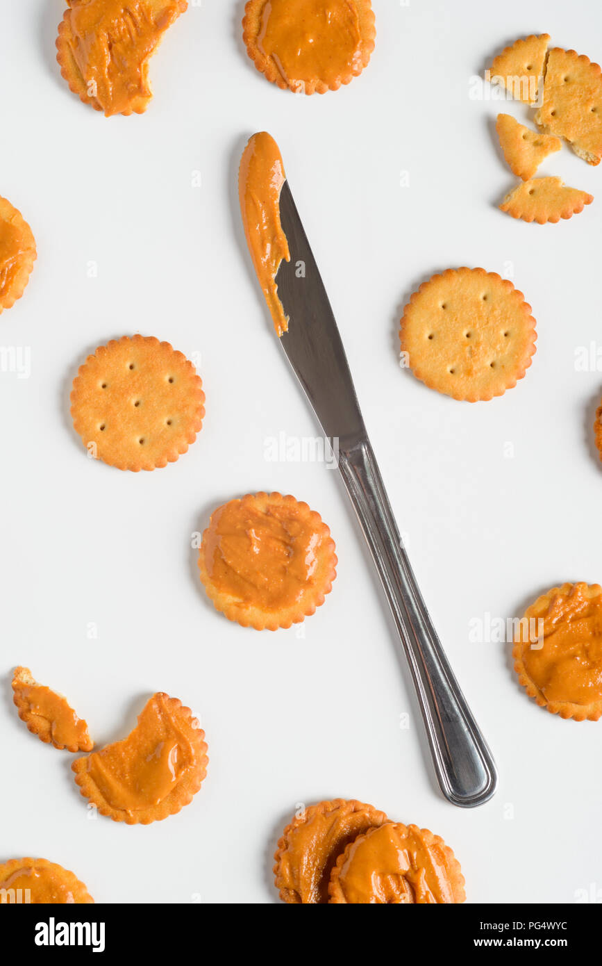Fantastic crackers with peanut butter, close-up. Knife, white wooden ...