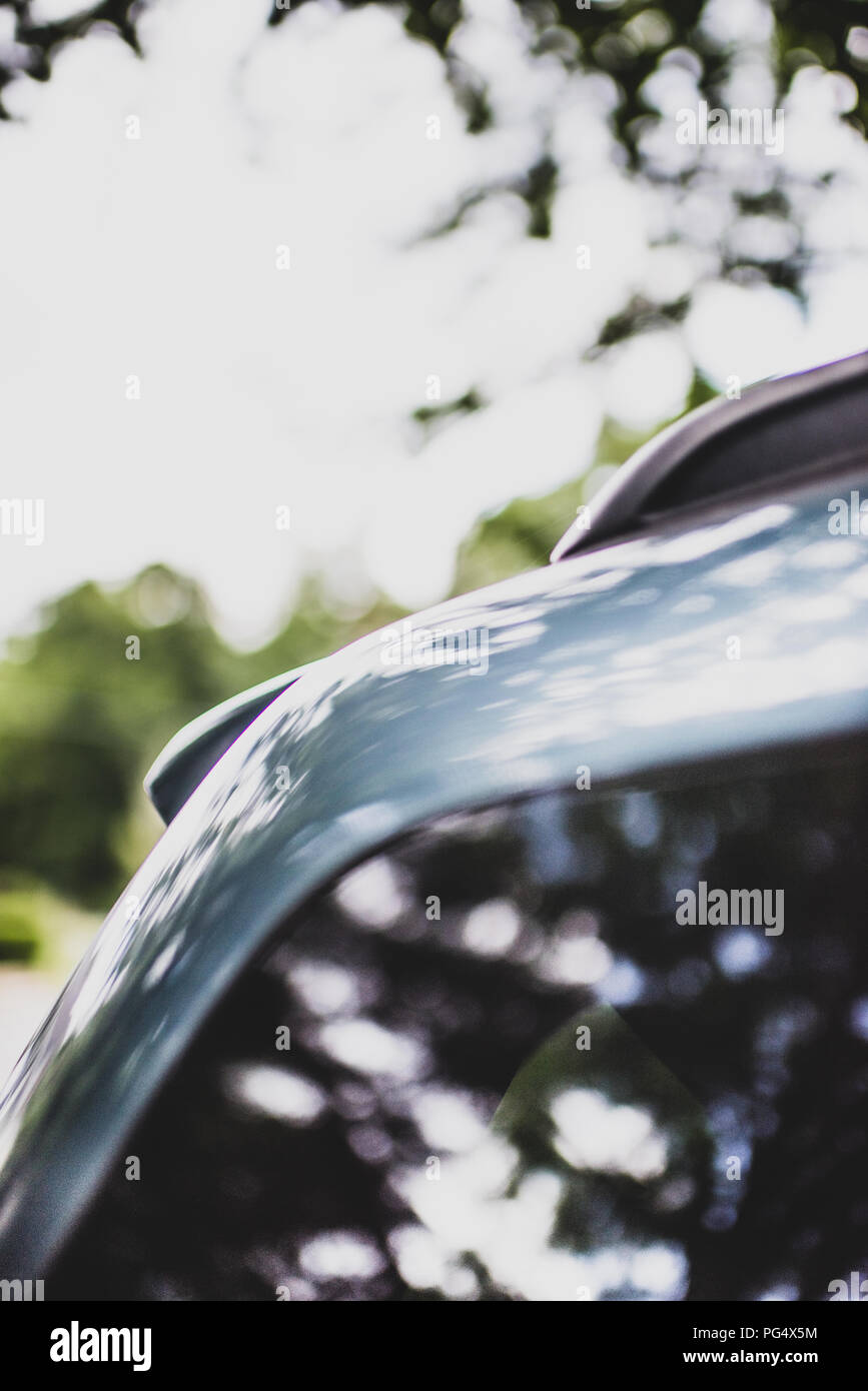 Top of a car with mostly sky and trees showing, lots of bokeh, blue car ...