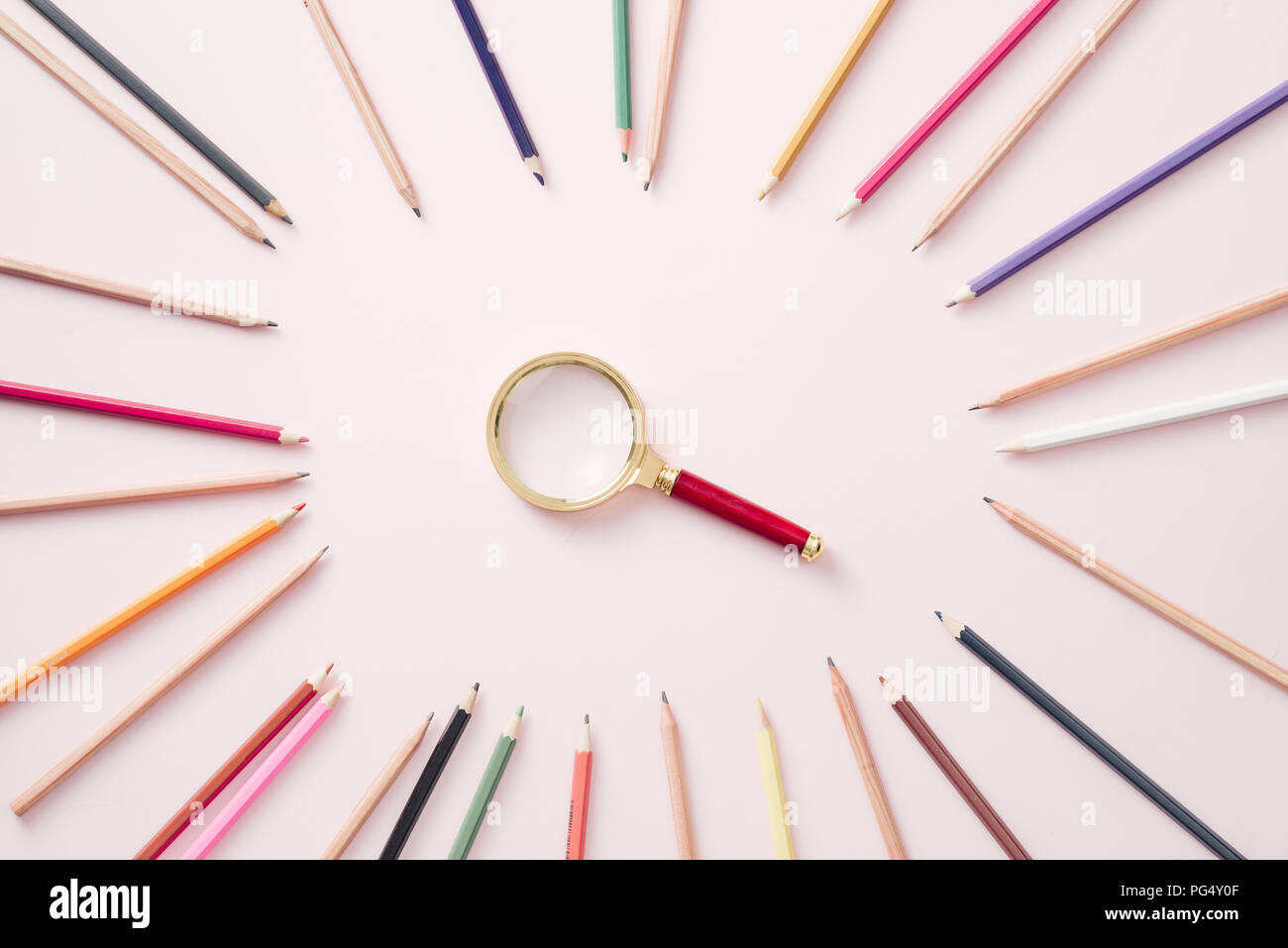 Magnifier in center with Bright colored pencils lined around the ...