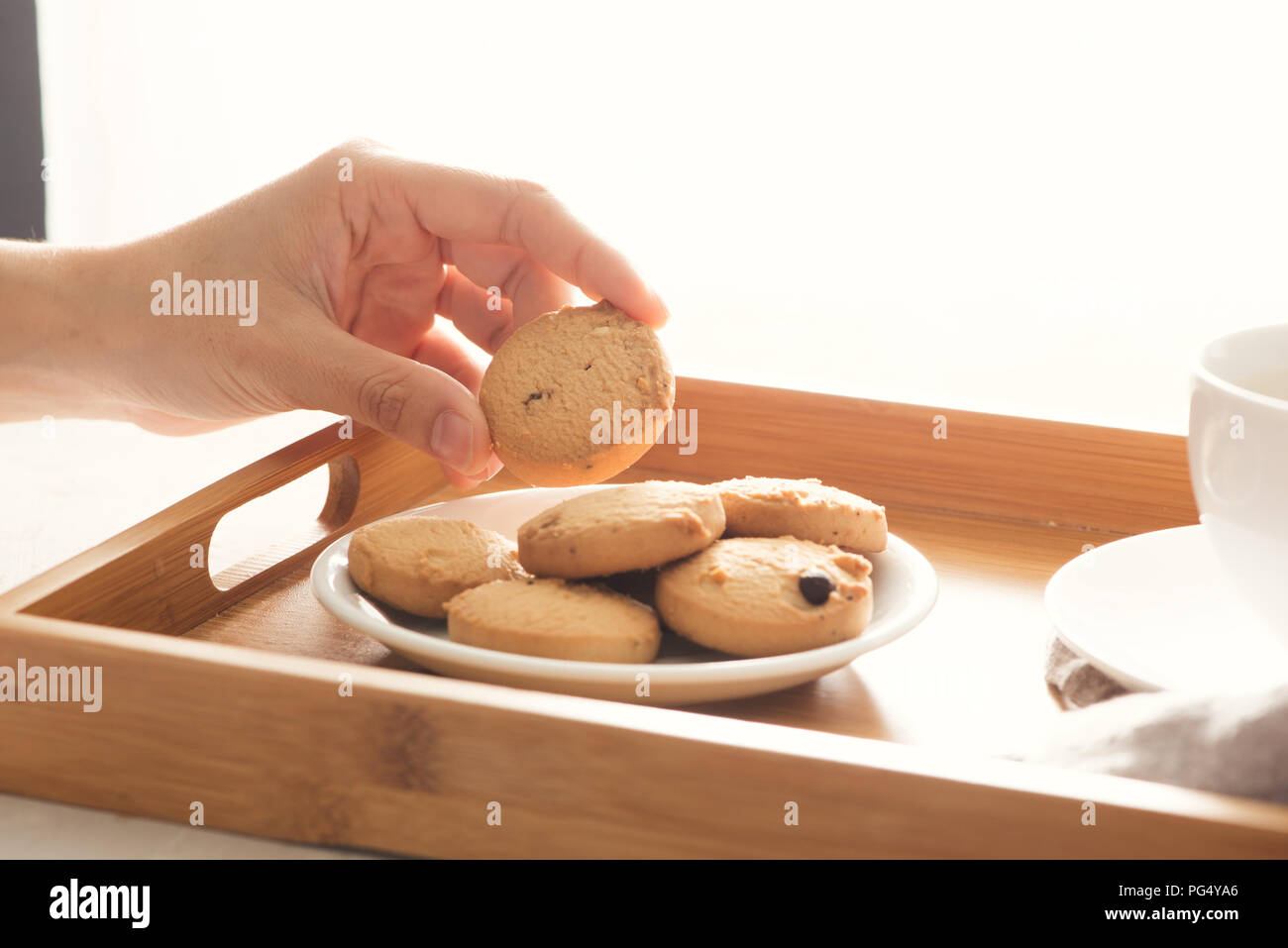 Hand picking cookie from plate in tray Stock Photo - Alamy
