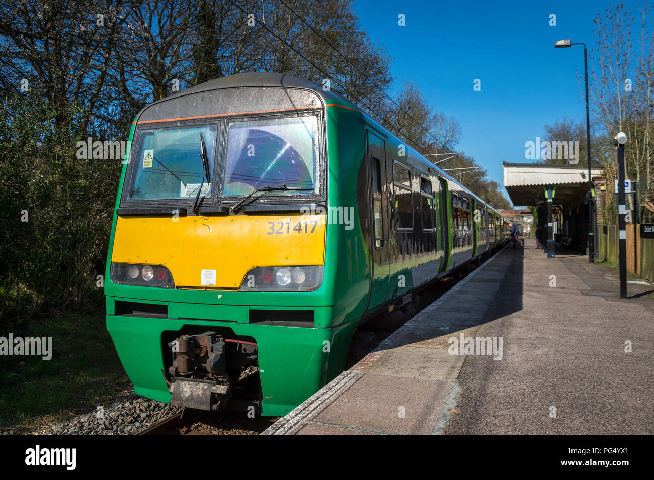 Class 321 passenger train in London Midland livery waiting at a small railway station on the ...