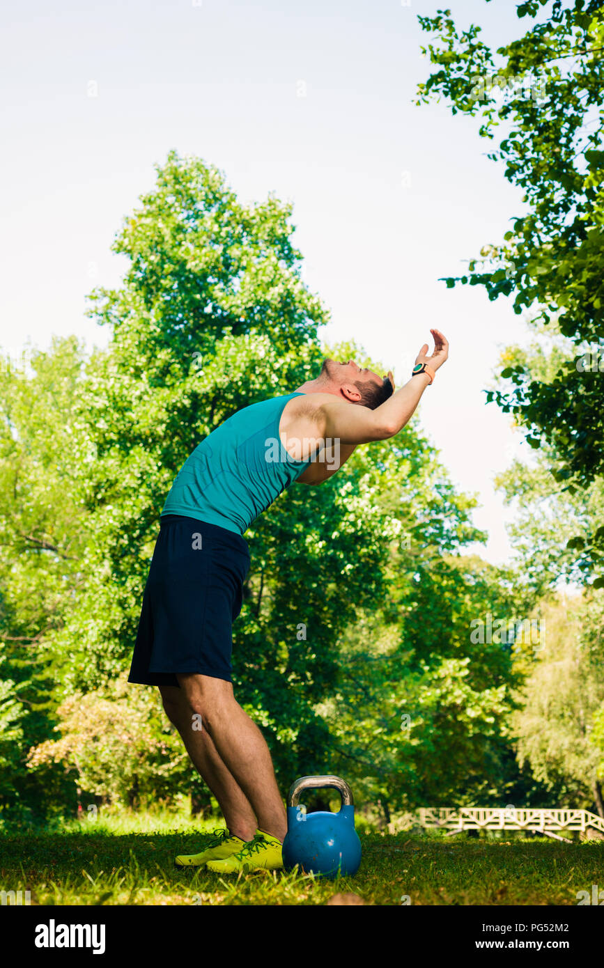 Fit man warming up before start to exercise with kettlebell into the ...