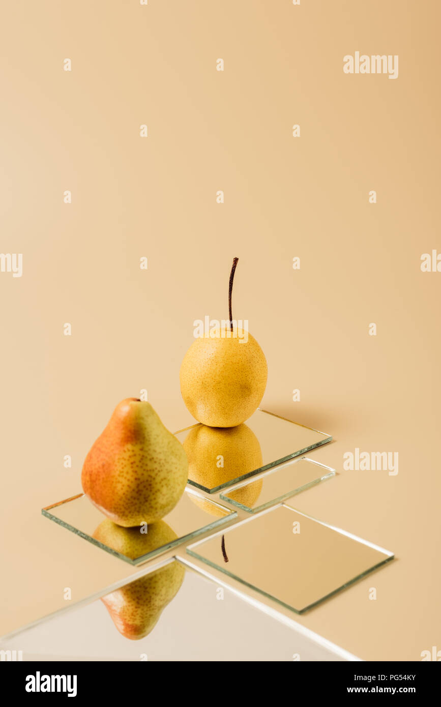 two yellow pears reflecting in mirrors on beige table Stock Photo - Alamy