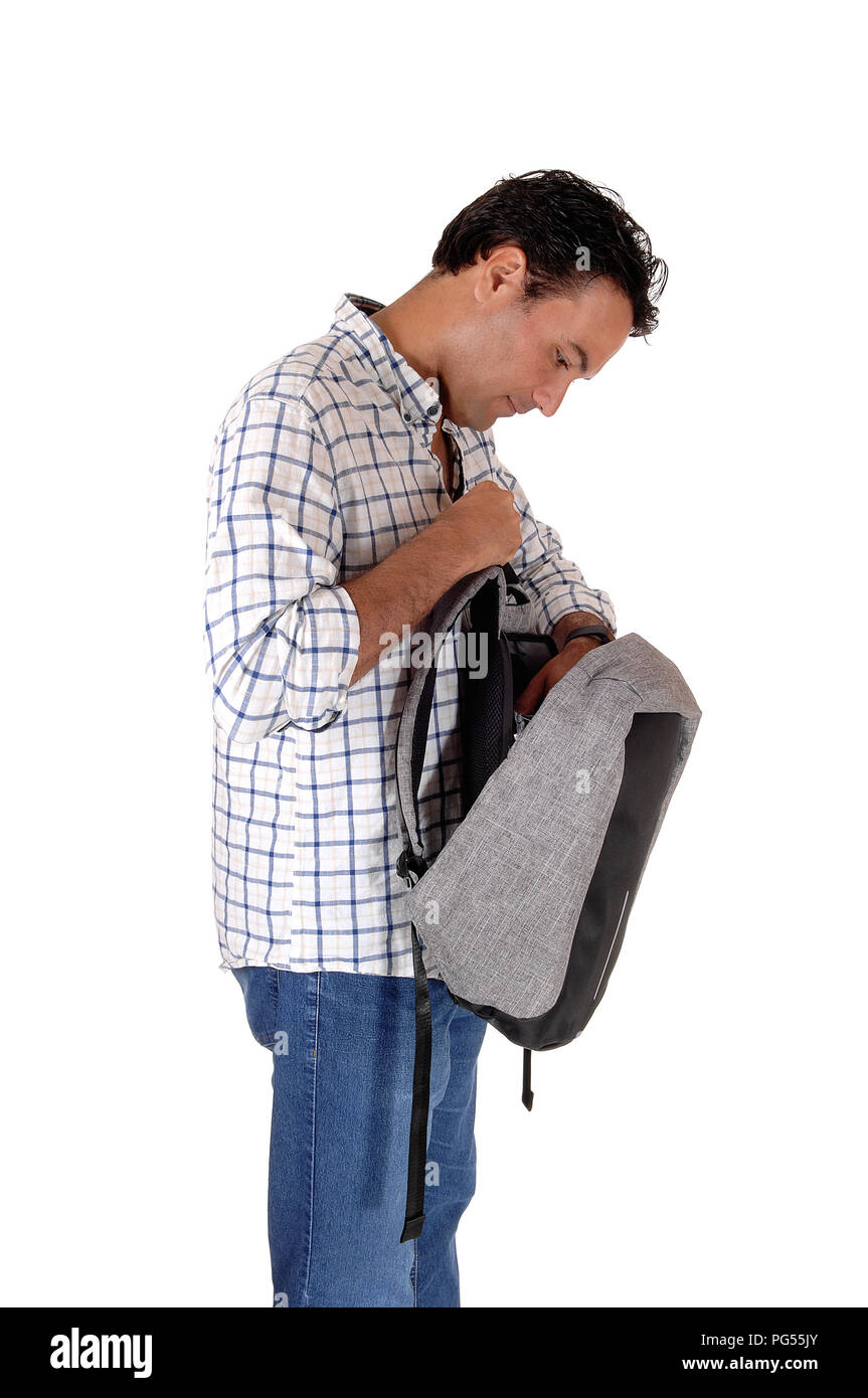 A handsome young man standing in profile looking into his open backpack ...