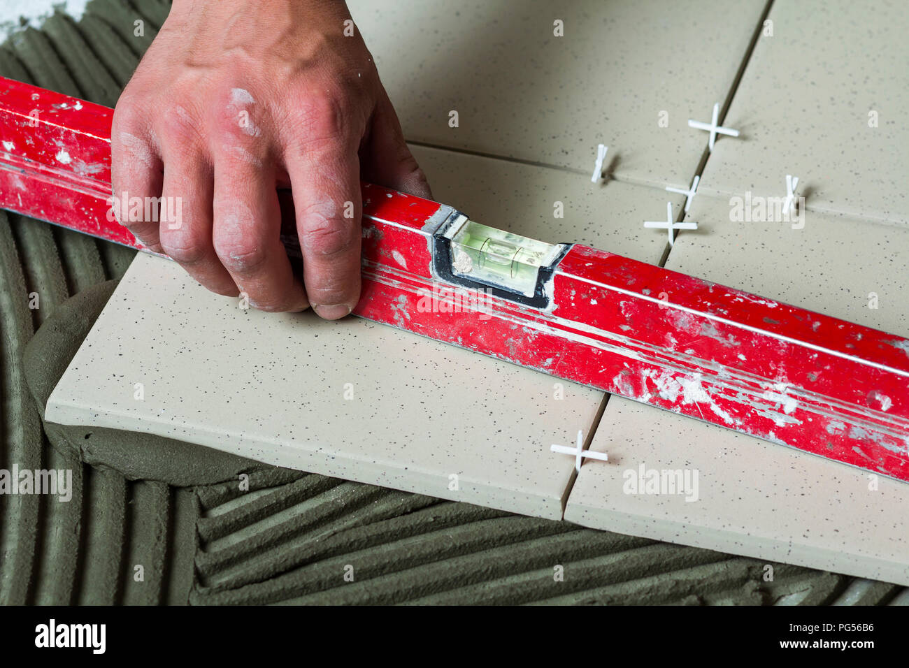 Ceramic tiles and tools for tiler. Worker hand installing floor tiles ...