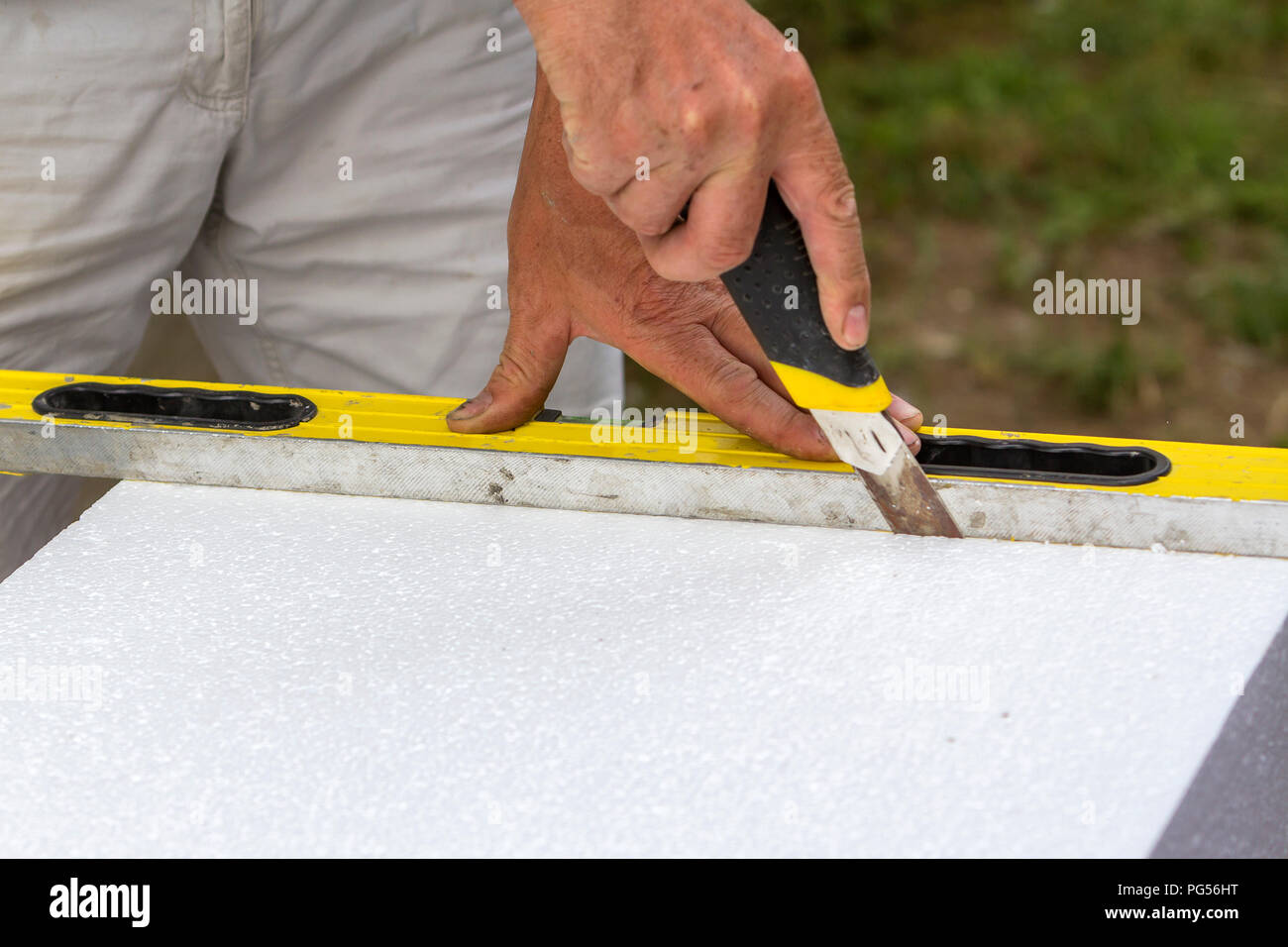 Close-up of worker hand with knife and level cutting white rigid ...
