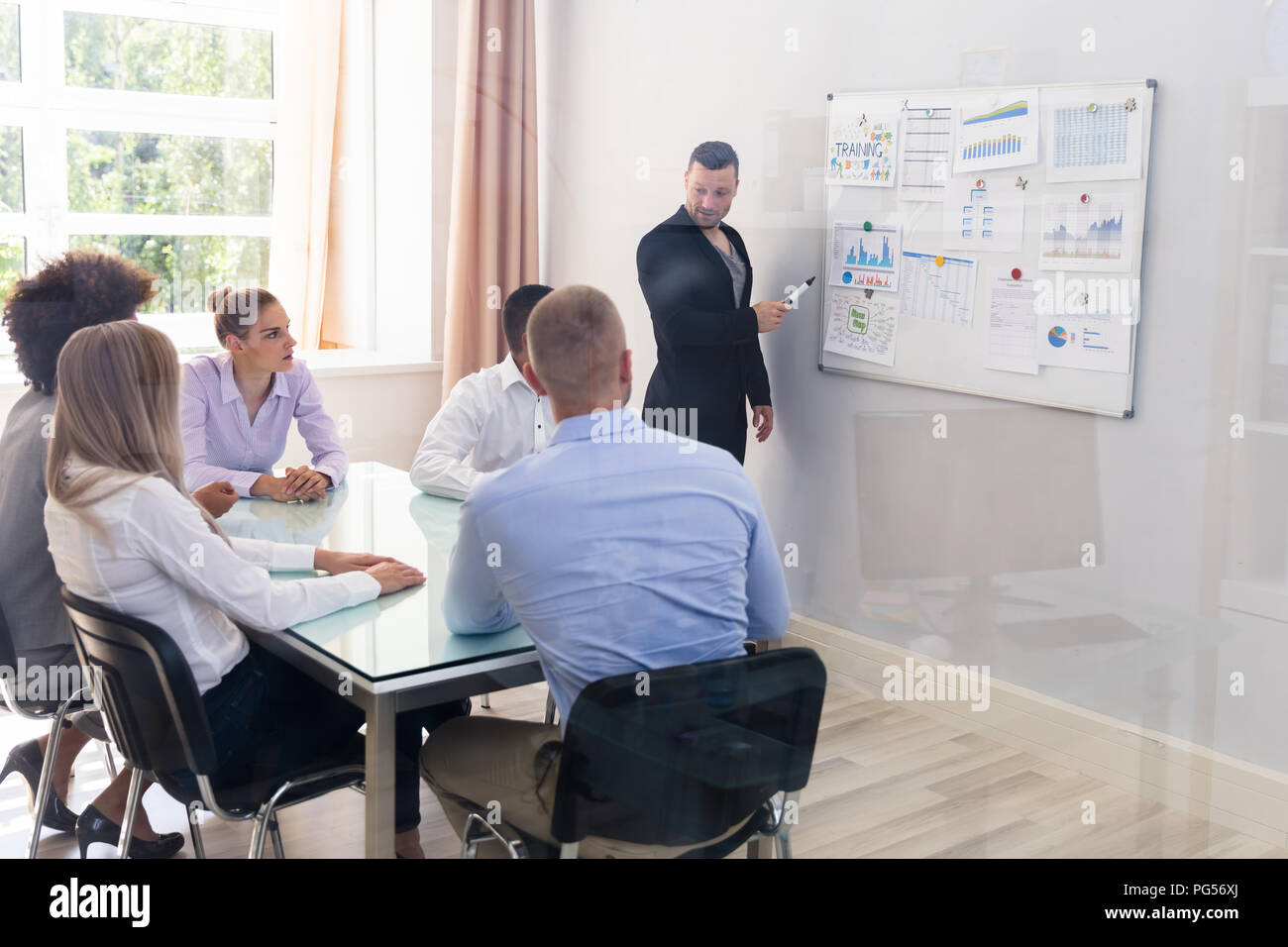 Young Businessman Explaining Graphs To His Colleagues At Workplace ...