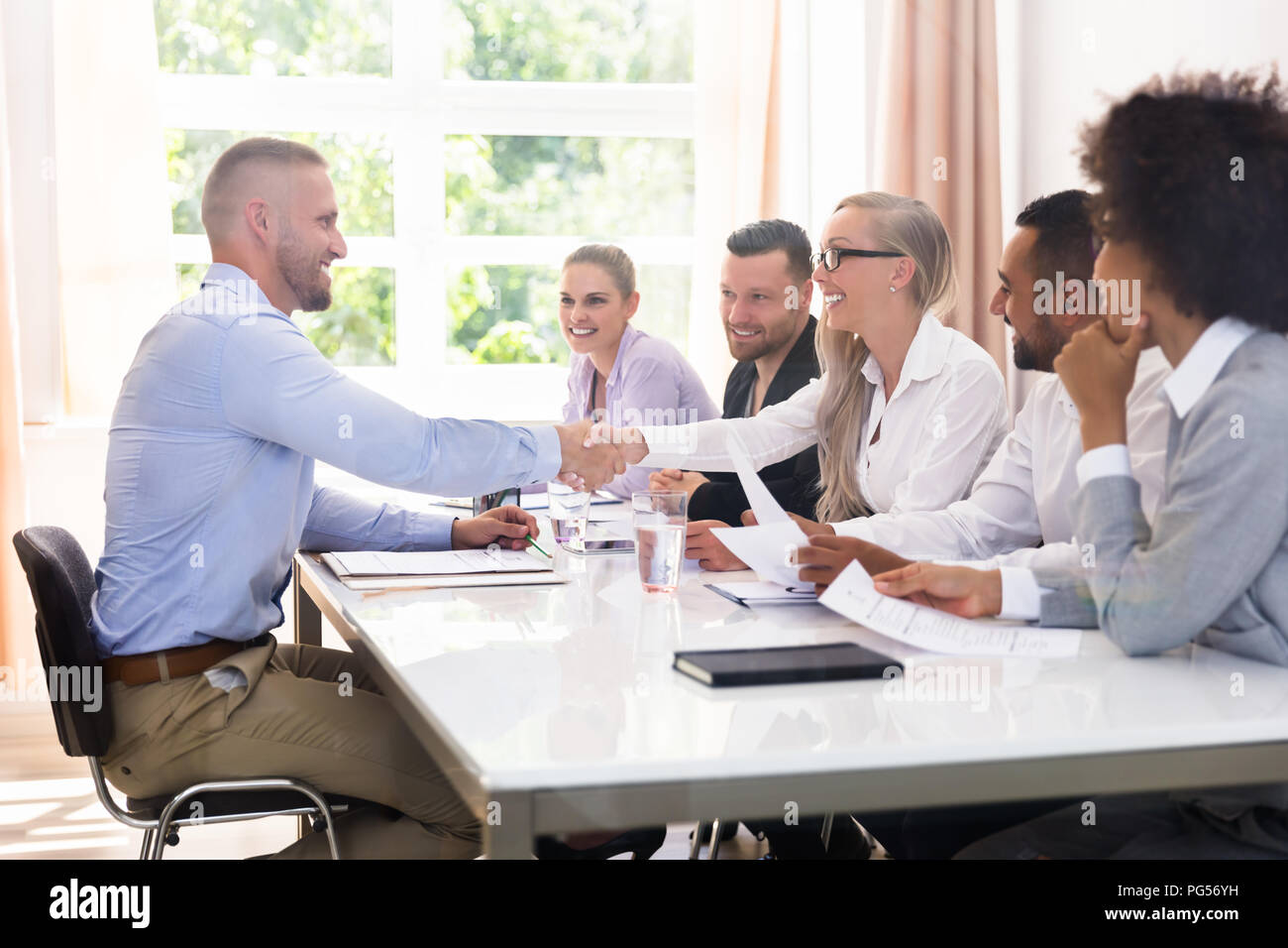 Smiling Young Man Shaking Hands With Female At Interview Stock Photo ...