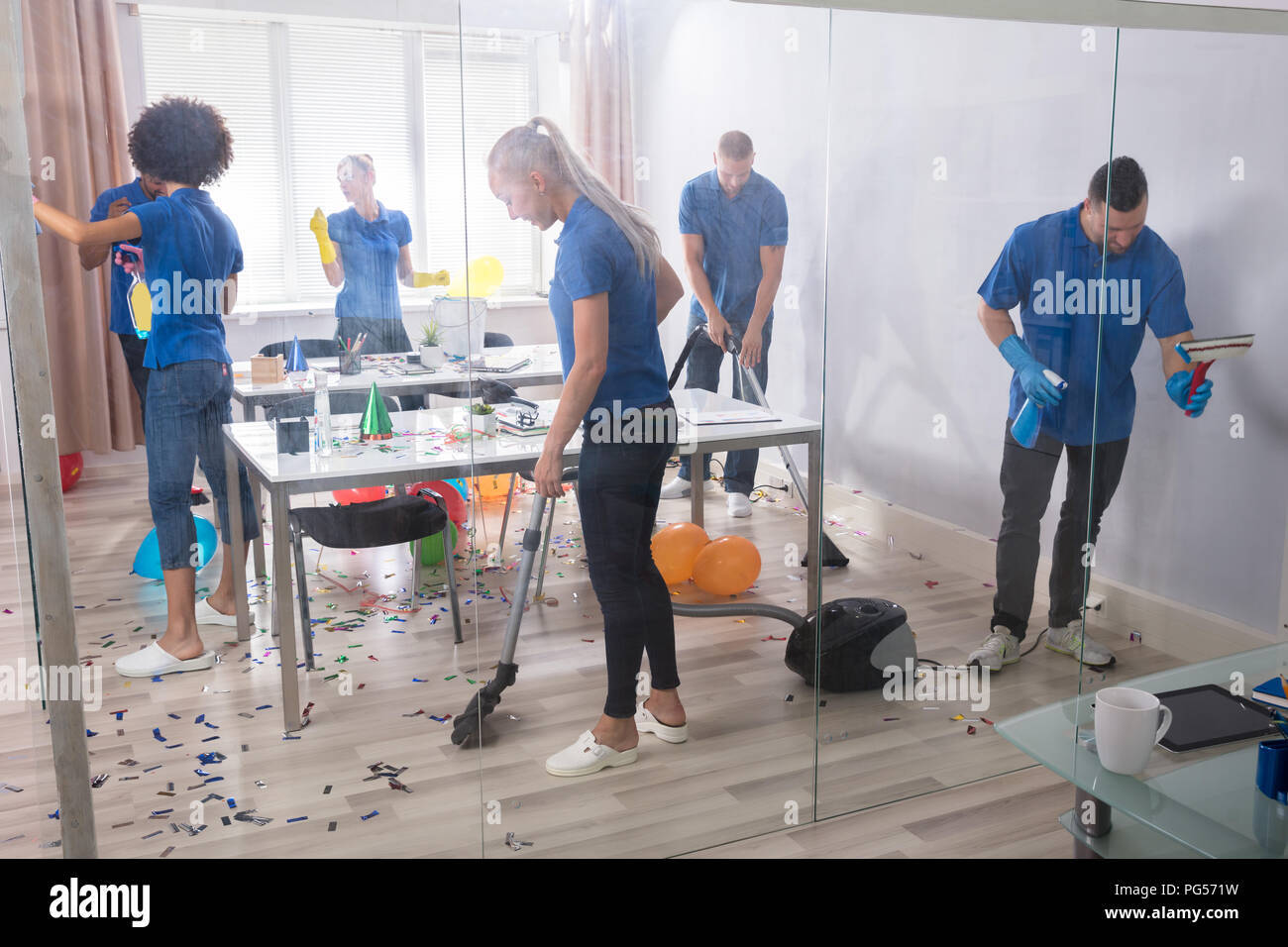 Group Of Janitors In Uniform Cleaning Messed Up Office Stock Photo - Alamy