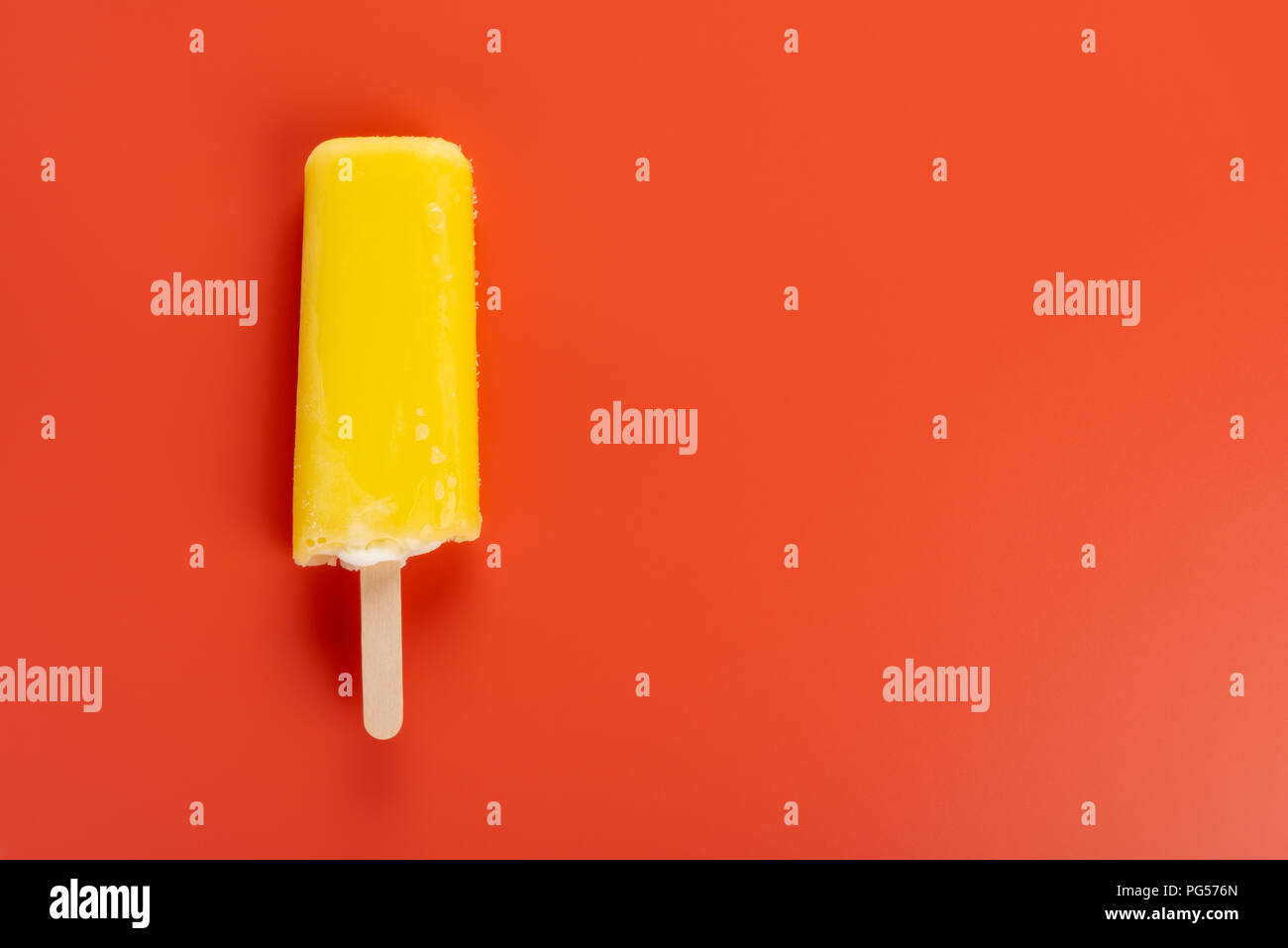 yellow popsicle on a red background Stock Photo - Alamy