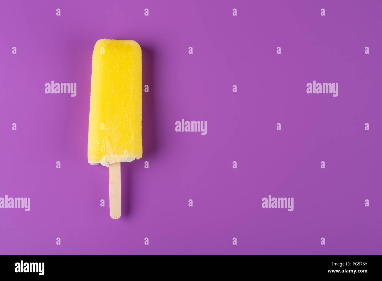 yellow popsicle on a purple background Stock Photo - Alamy