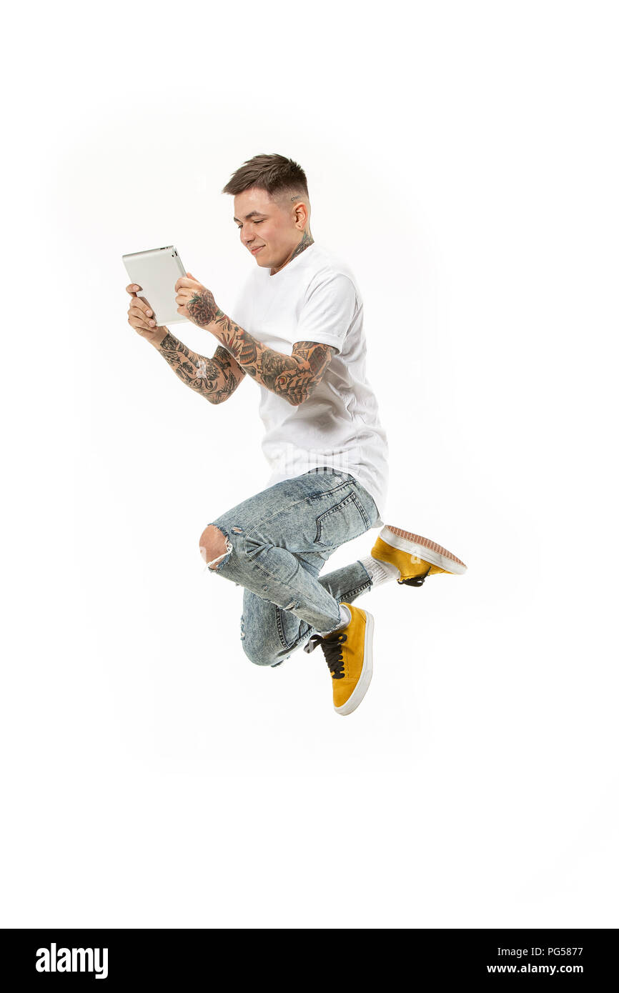 Jump of young man over white studio background using laptop computer ...