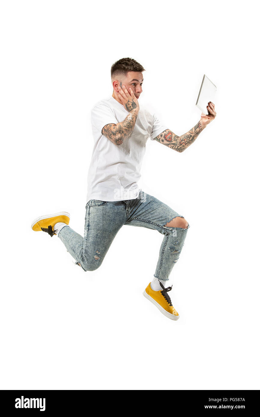 Jump of young man over white studio background using laptop computer ...