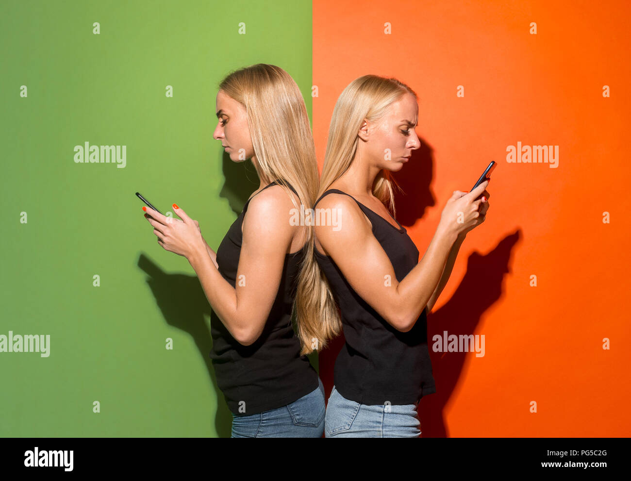 Portrait of a confident happy smiling casual girls with mobile phones over studio background ...
