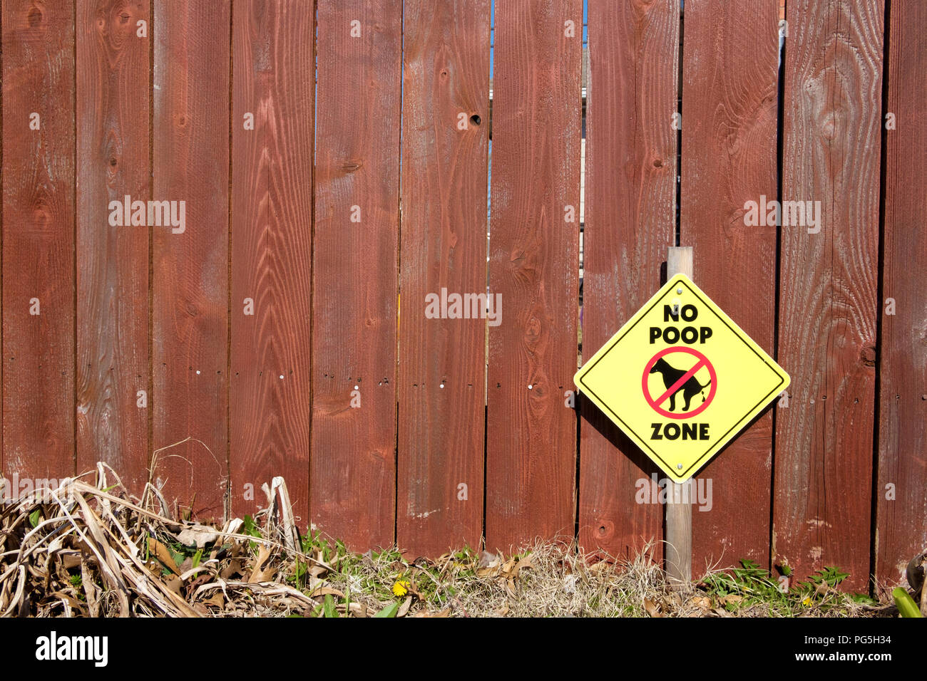 Brown wooden garden fence with the sign “No Poop Zone” and illustration ...