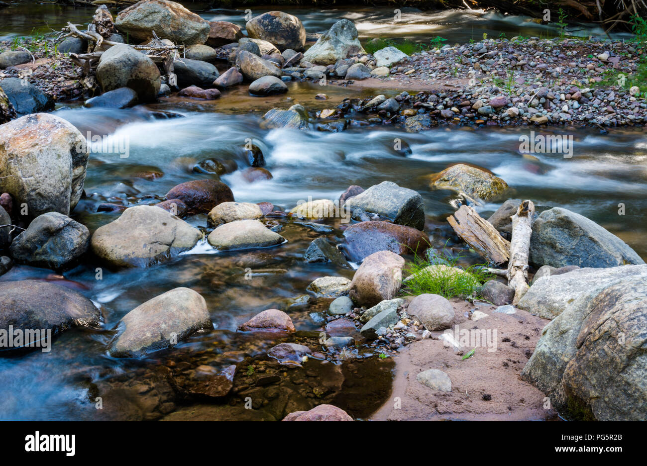 Spring creek with boulders and blue water Stock Photo - Alamy