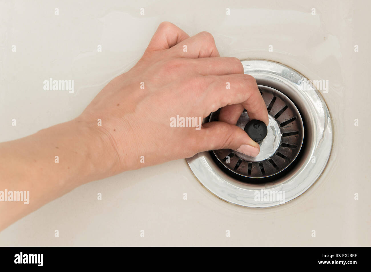 Woman hand pulls close cap of drainage hole of sink to drain water ...
