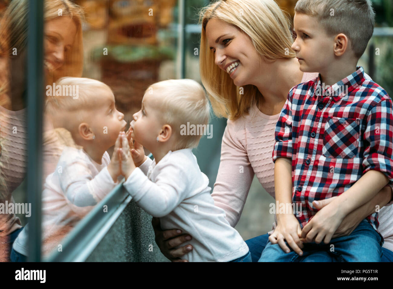 Mother with little girl and boy looking through shop window Stock Photo ...