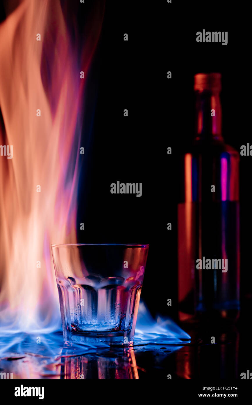 close up view of flame, empty glass and bottle of sambuca alcohol drink ...