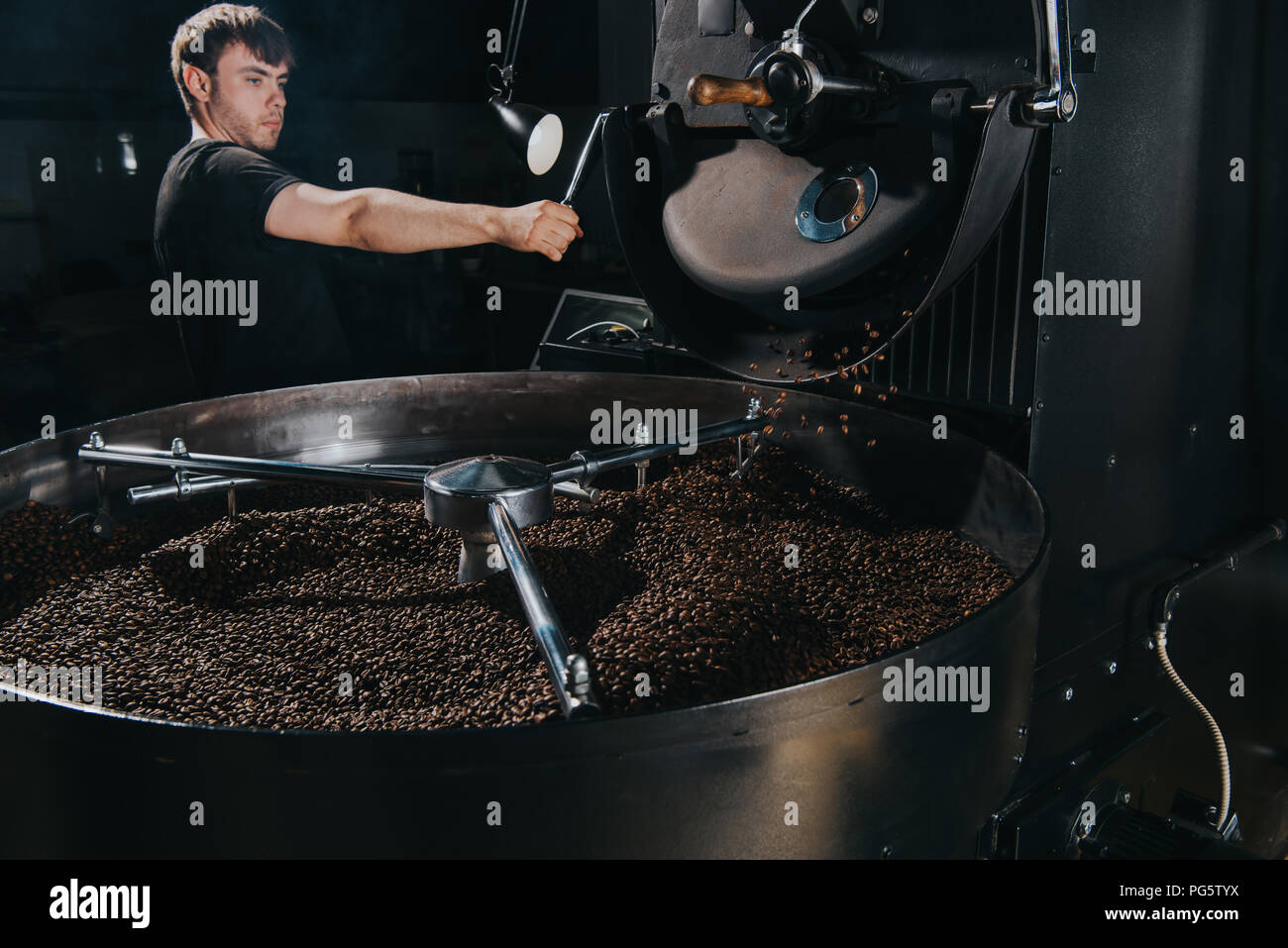 Professional male roaster working with industrial roasting machine ...