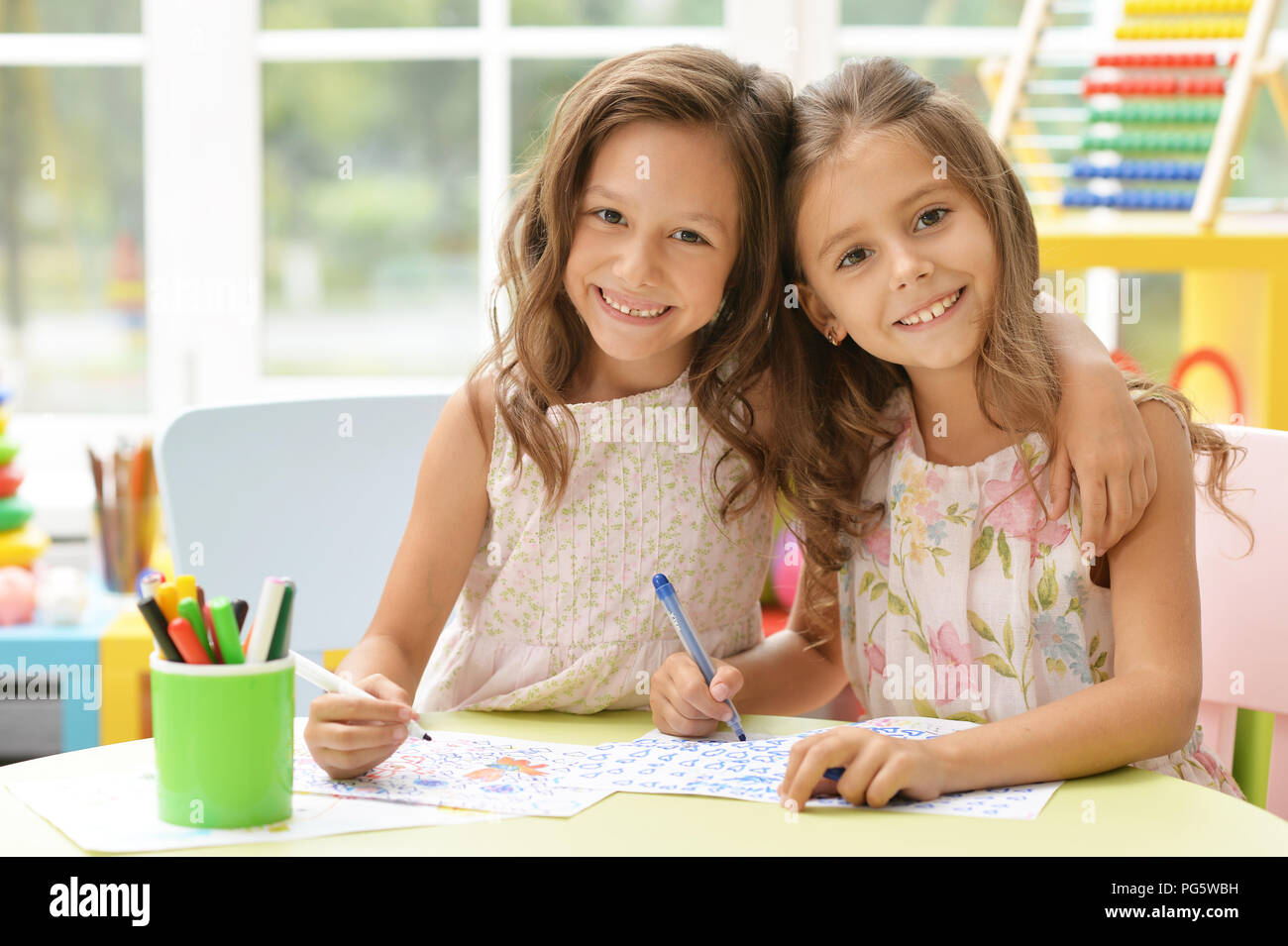 Portrait of two cute little girls drawing together Stock Photo - Alamy