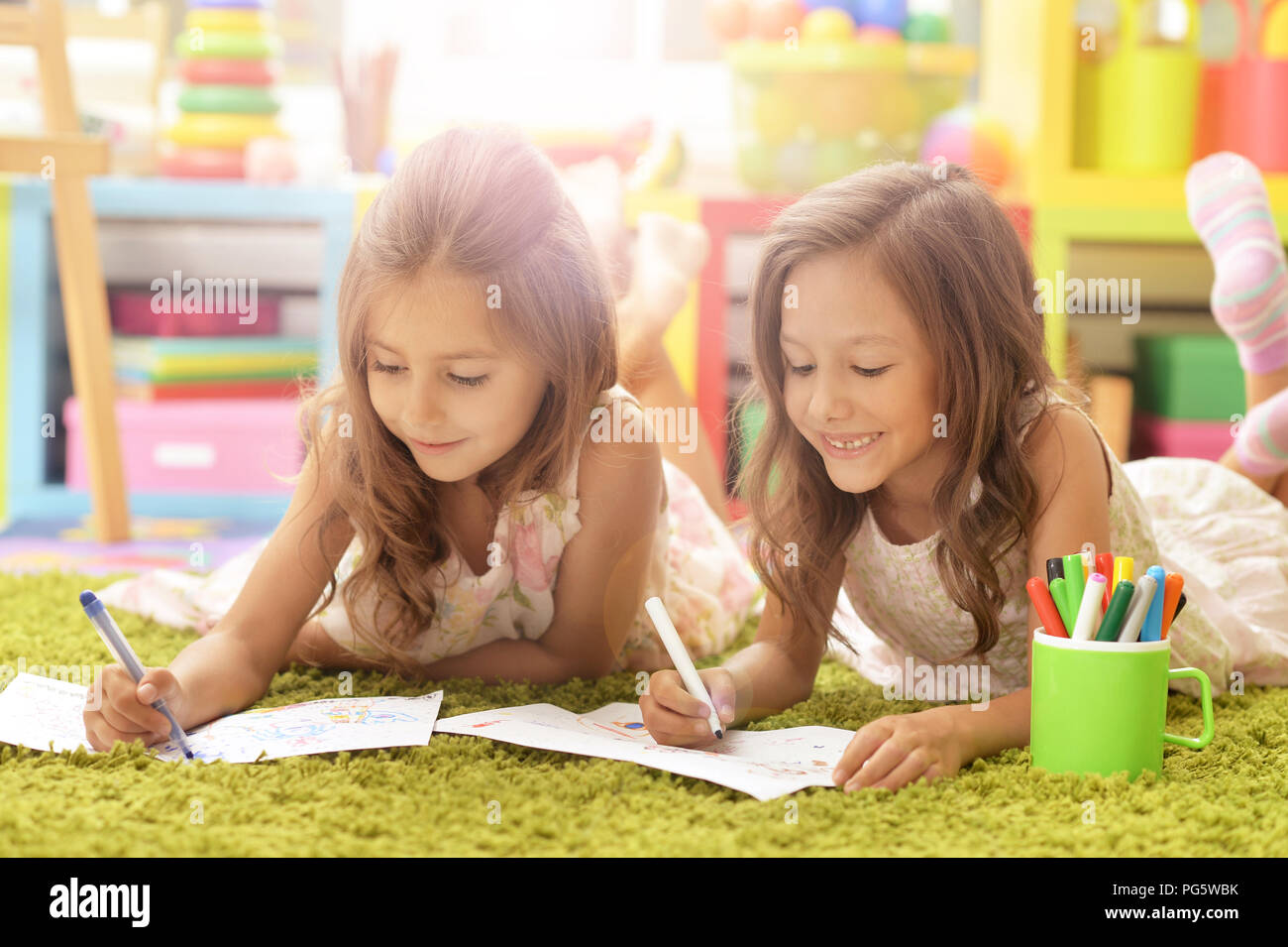 Portrait of two cute little girls drawing together Stock Photo - Alamy