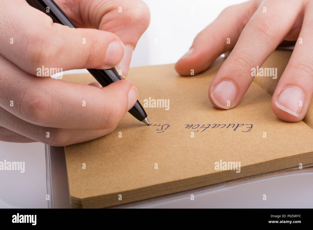 Hand writing 'Education is...' on a notebook Stock Photo - Alamy