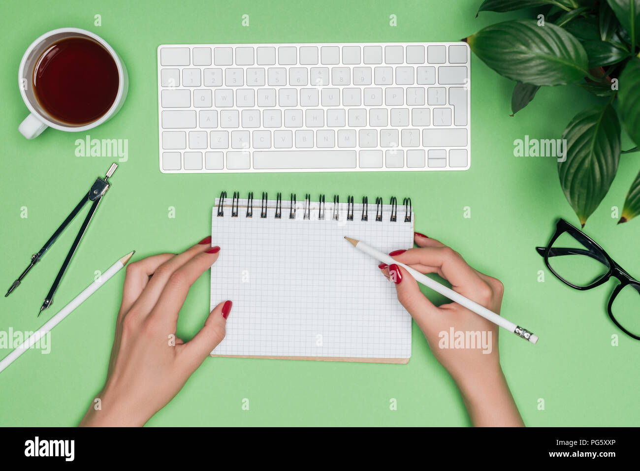 cropped image of female architect writing in empty textbook at table ...