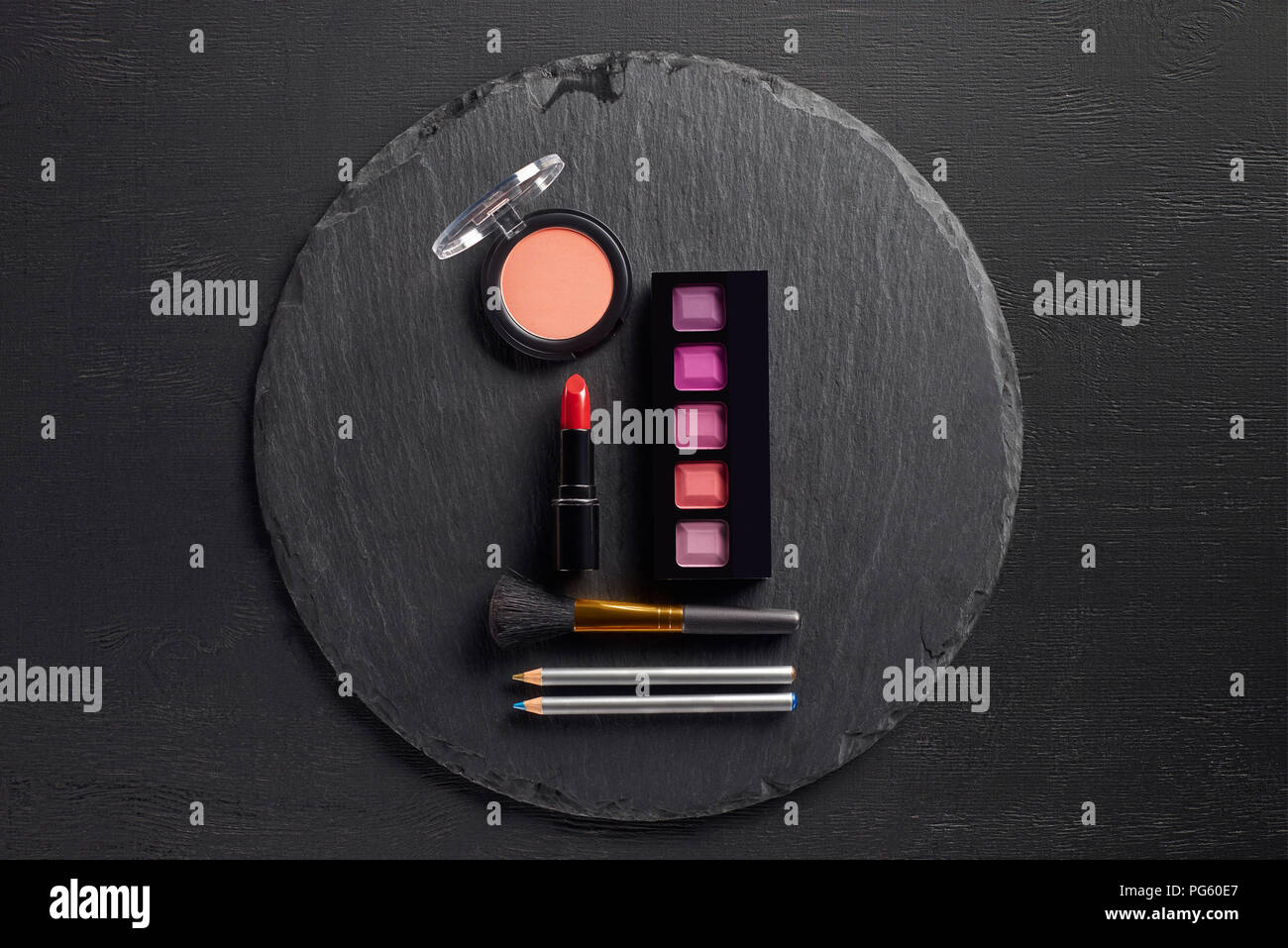 Make up template with eye shadows and lipstick on round slate ...