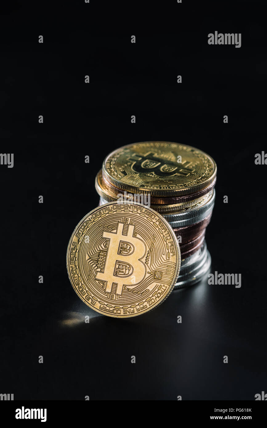 close up view of bitcoin leaning on stack of various bitcoins on black ...