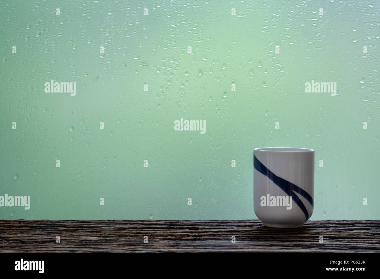 Japanese tea cup on wood inside glass windows on the background of wet ...