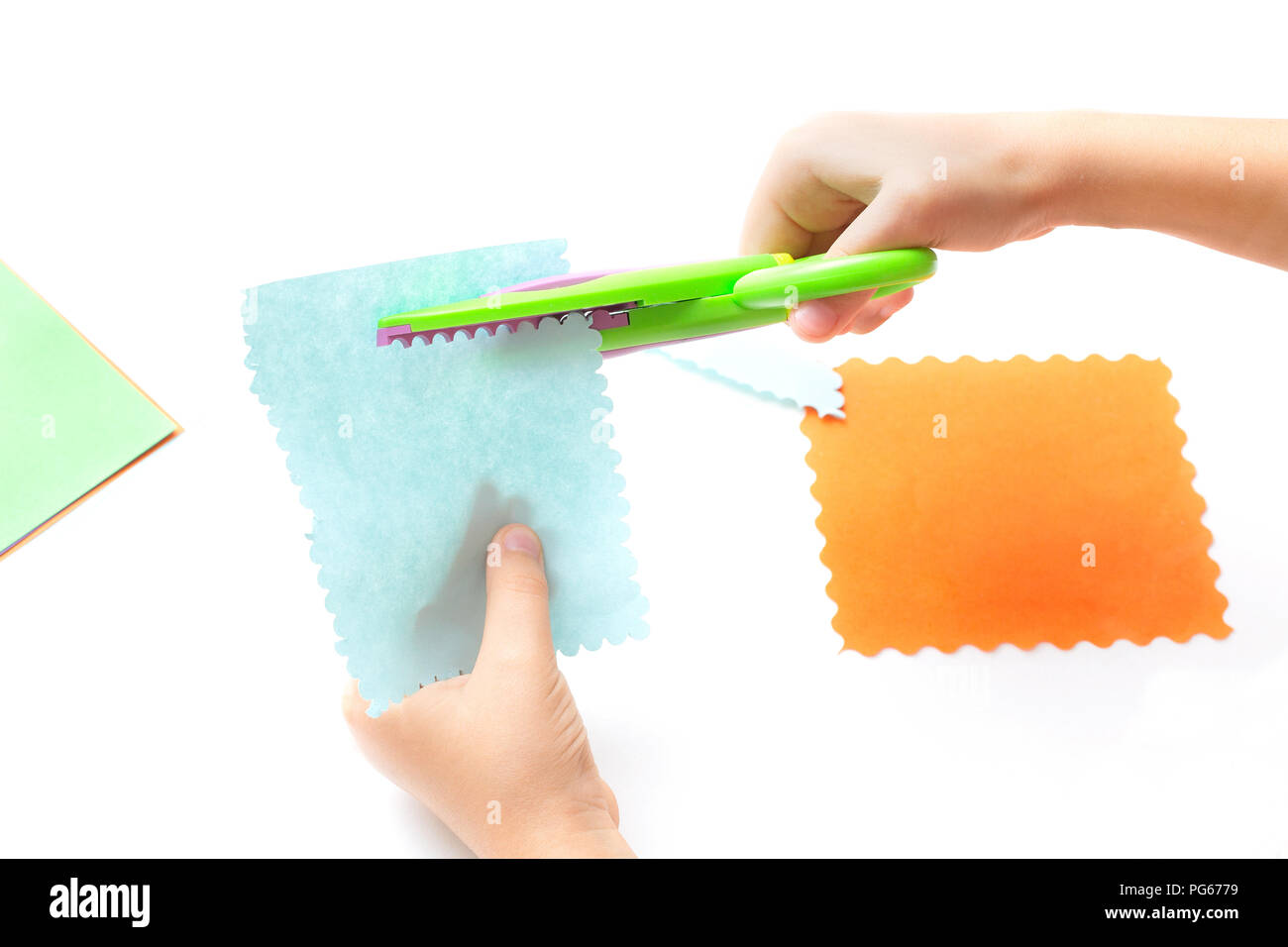 Children's hands cut out colored paper with figured scissors ...