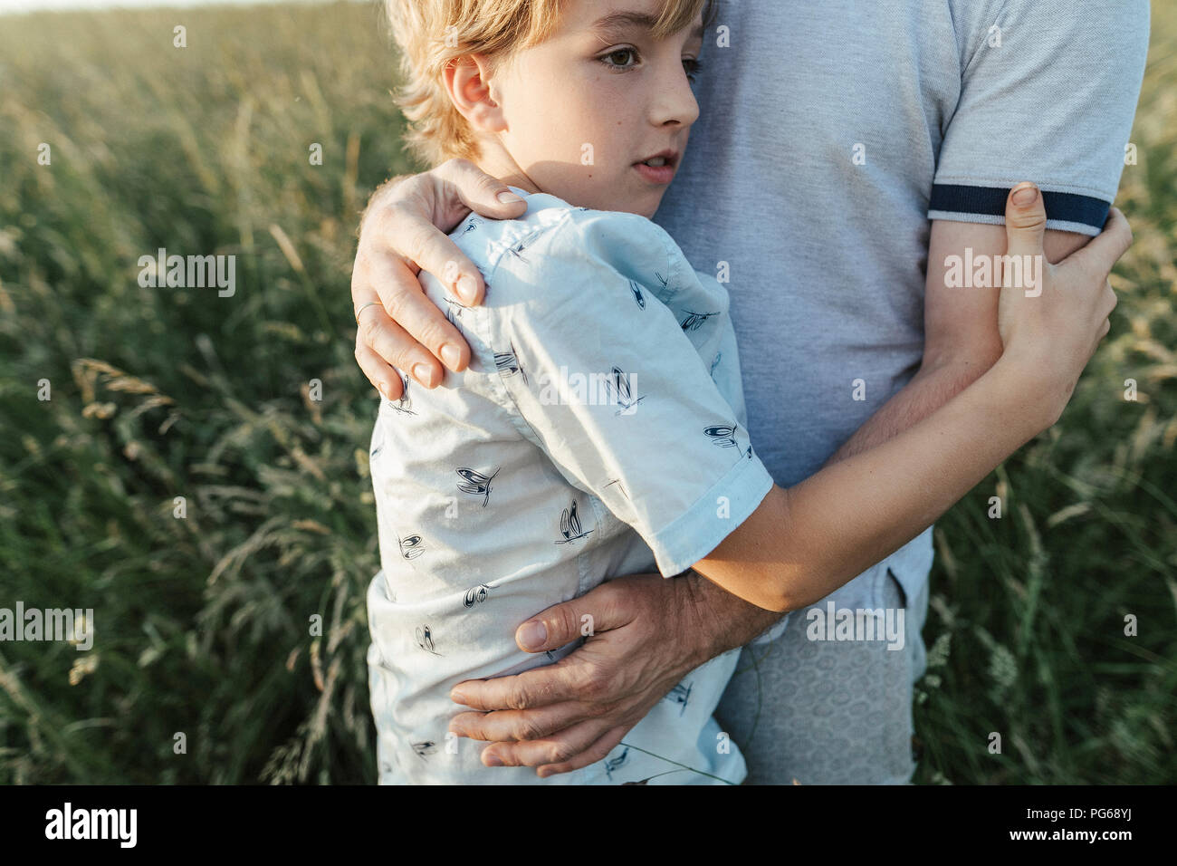 Boy hugging his father on a meadow Stock Photo - Alamy
