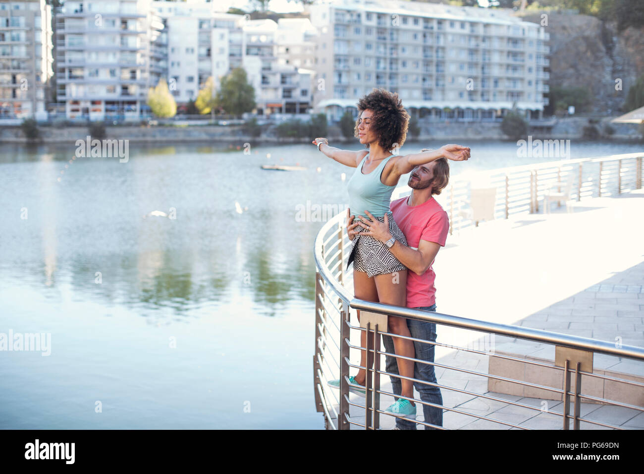 Woman balancing on railing with eyes closed, while man is holding her ...