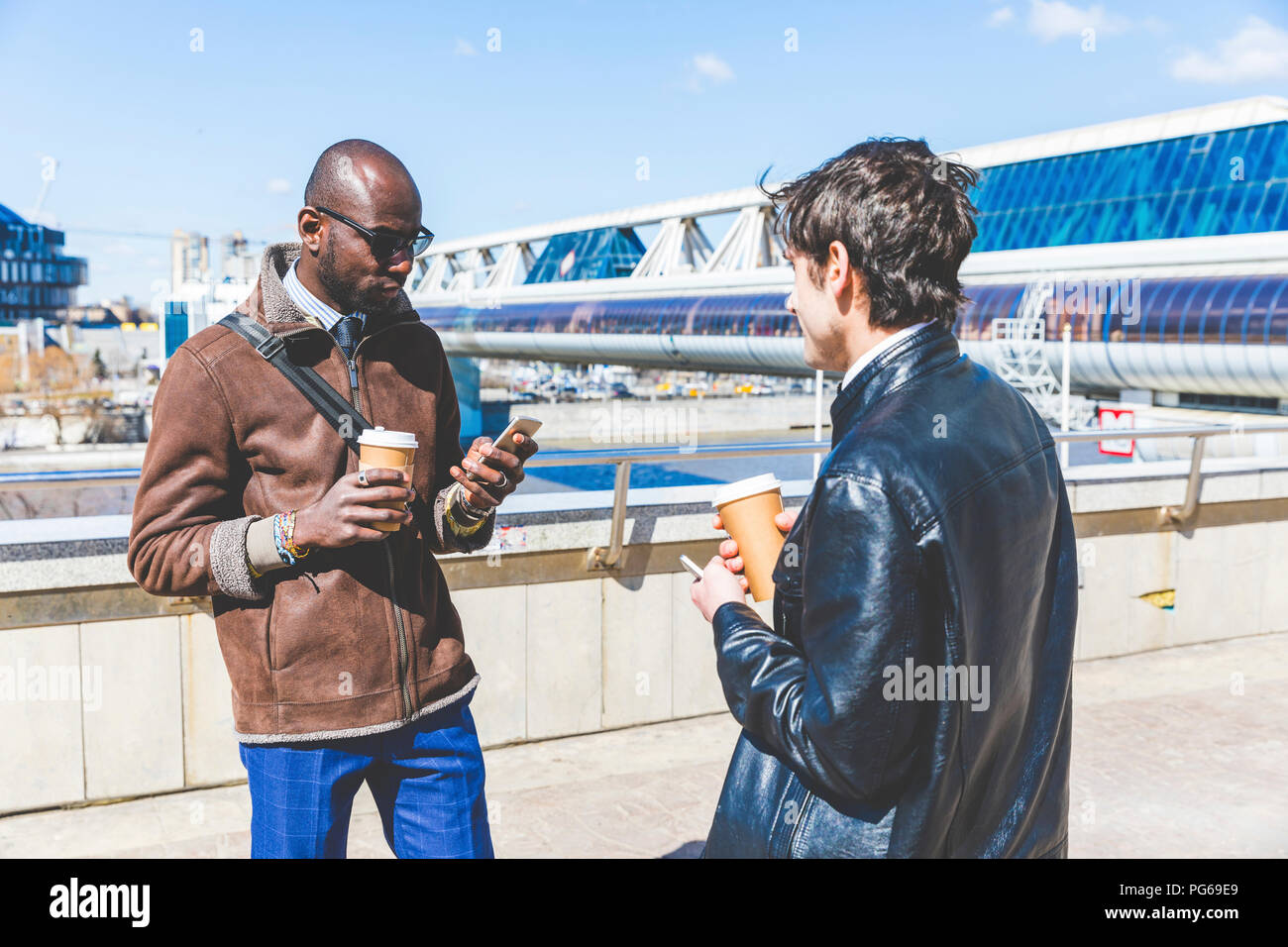 Russia, Moscow, two businessmen with coffee to go and smartphone in the ...
