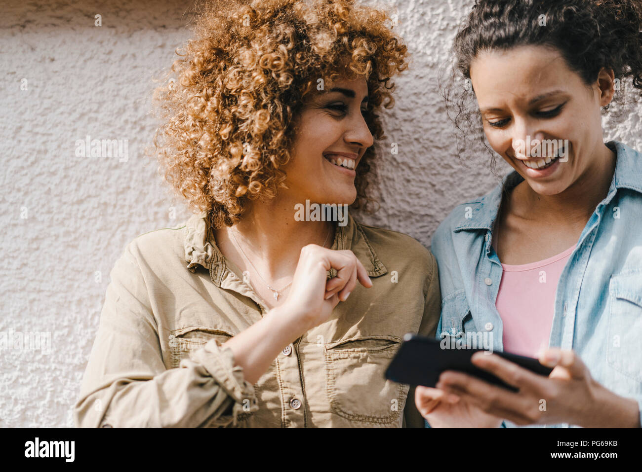 Two female friends with cell phones in the city hi-res stock ...